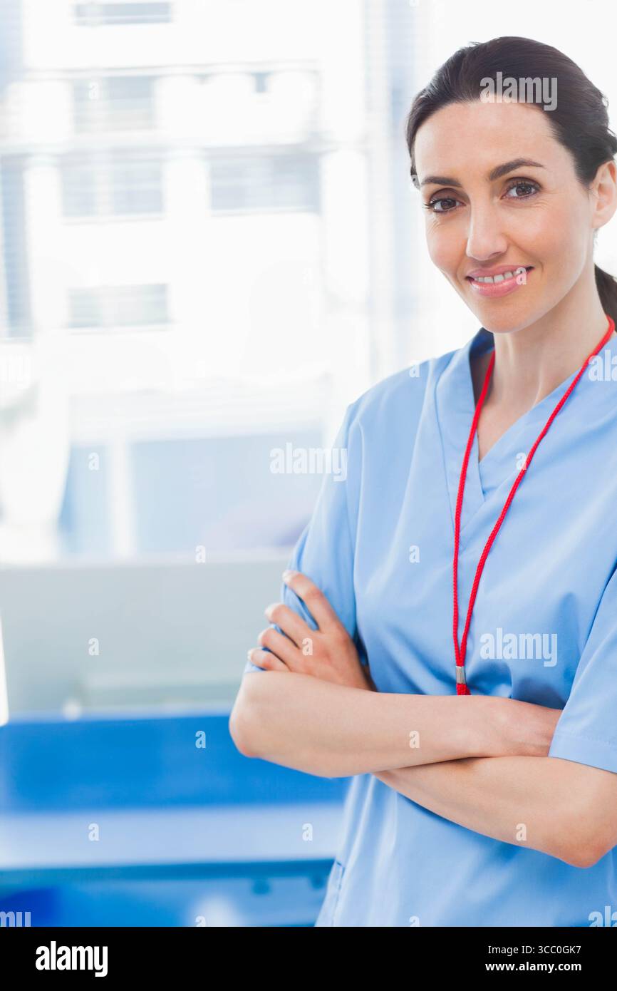 Female nurse standing arms crossed in clinic wearing blue scrubs with ...