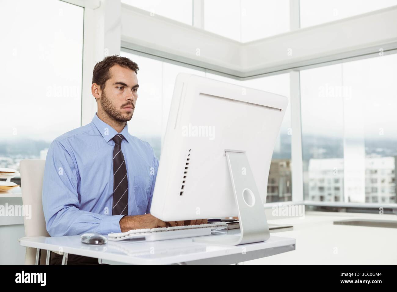 Businessman typing on all-in-one desktop computer in office corner with ...