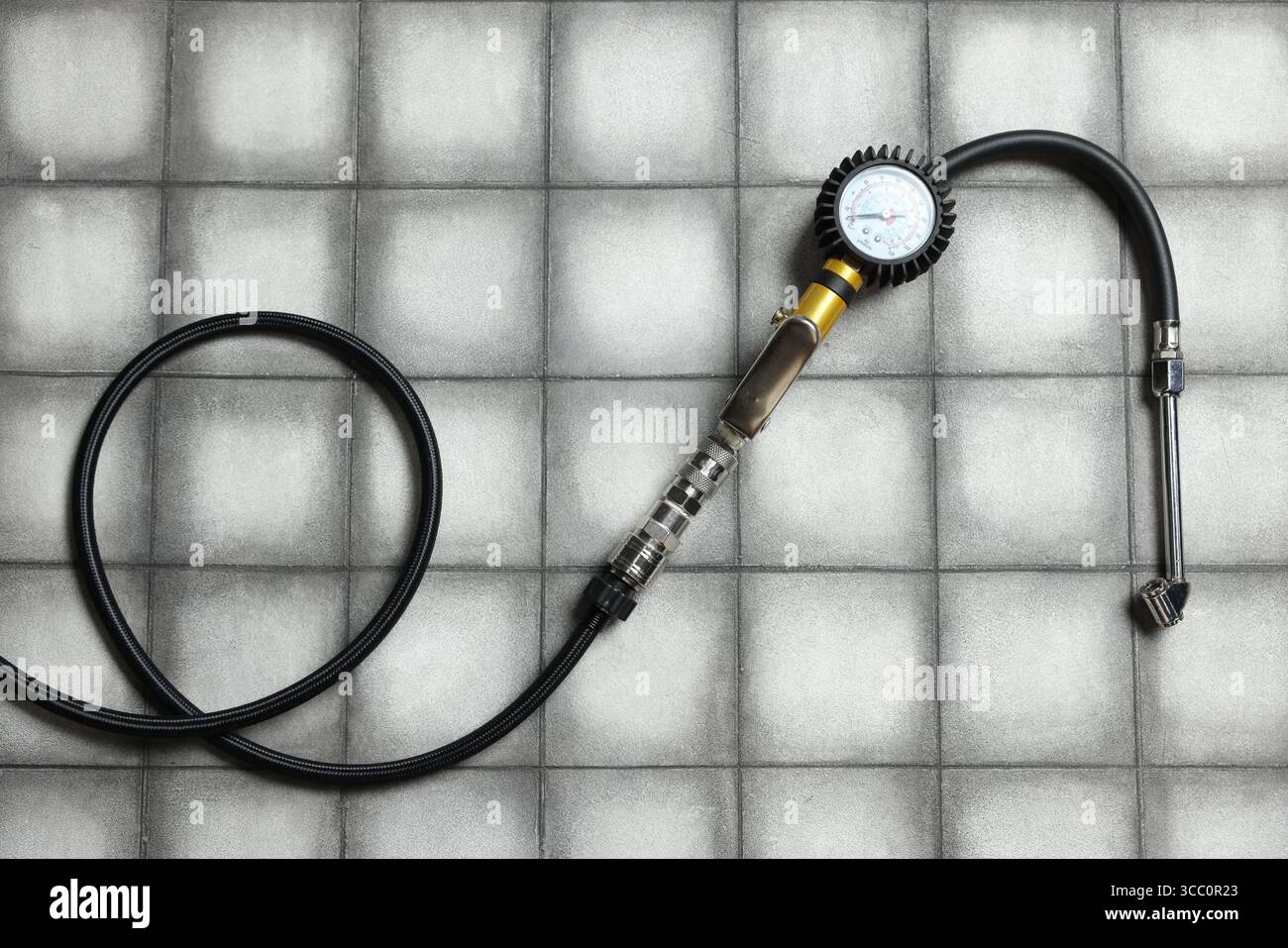One tire inflation gun with gauge on light tiled background, top view ...