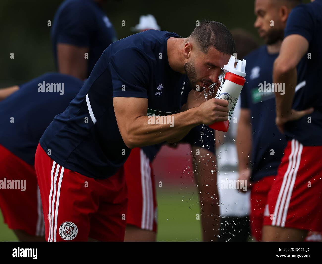Brackley, UK. 9th August 2025. Zak Lilly of Brackley Town sprays water ...