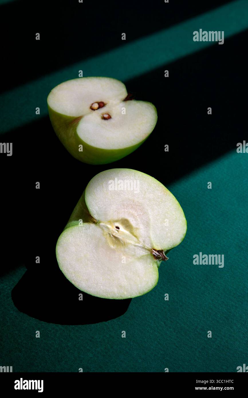 Minimalist composition of a fresh green apple cut in half, placed on a ...