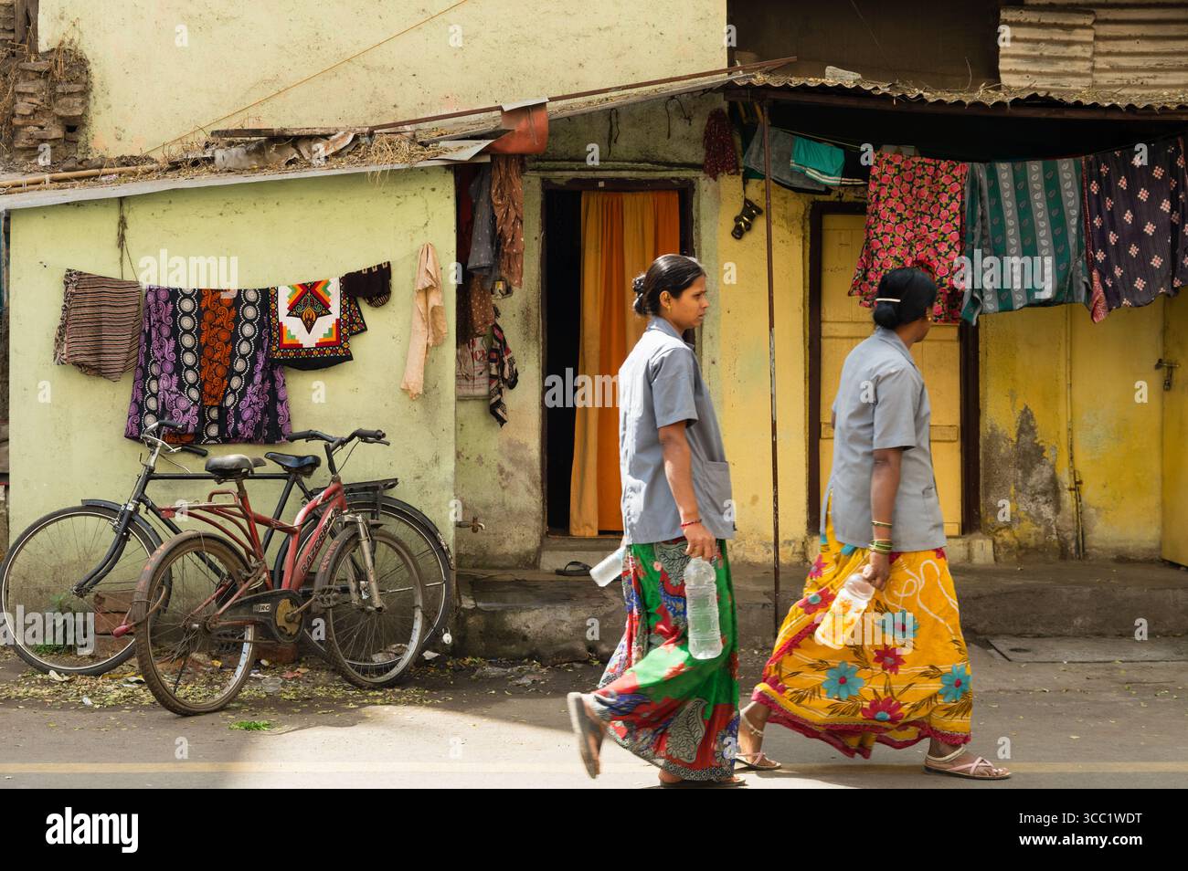 Two women walking past a poor house Stock Photo - Alamy
