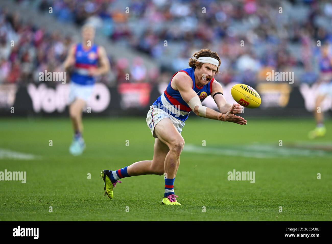 Oskar Baker of Western Bulldogs handballs the footy during the AFL ...
