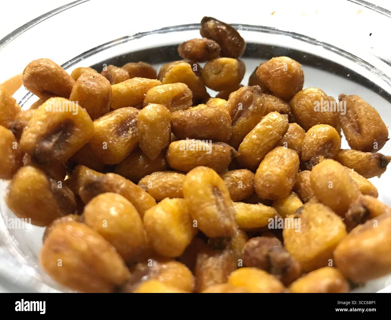 white plate and clear glass bowl with fried corn nuts Stock Photo - Alamy