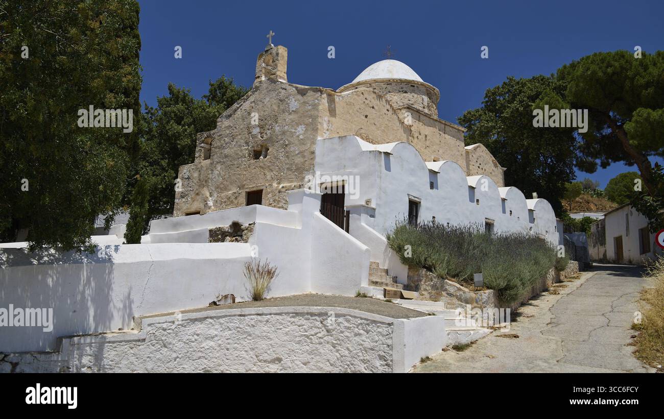 Whitewashed, stone church with dome and trees under a clear blue sky ...
