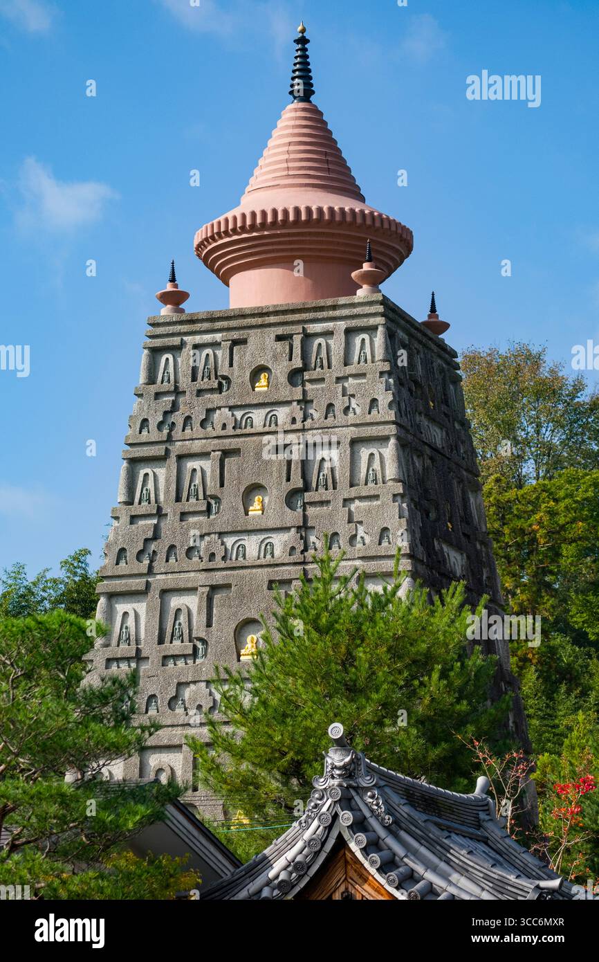 An ancient stone pagoda with ornate carvings stands amidst lush ...