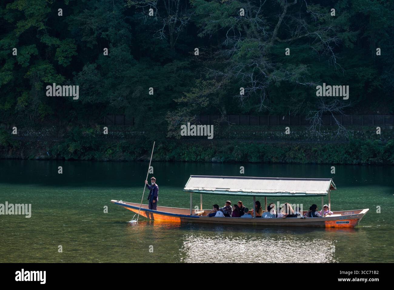A group of people enjoys a tranquil boat ride on a river surrounded by ...