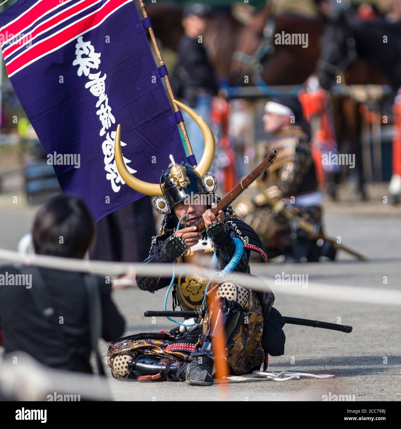 A samurai warrior in traditional armor kneels while giving gunnery ...