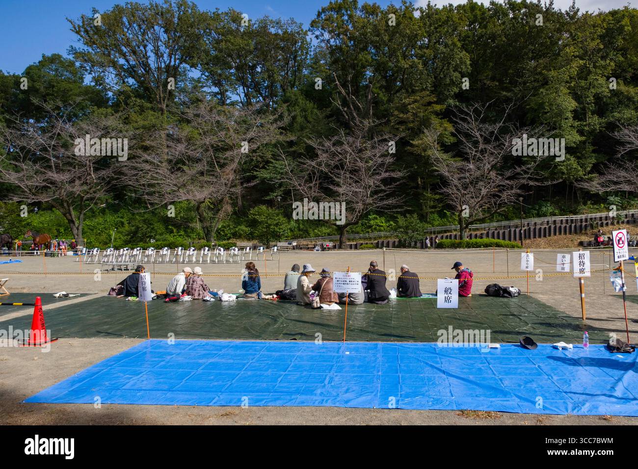 People sitting a tarp in the Multipurpose Plaza at Serigaya Park before ...