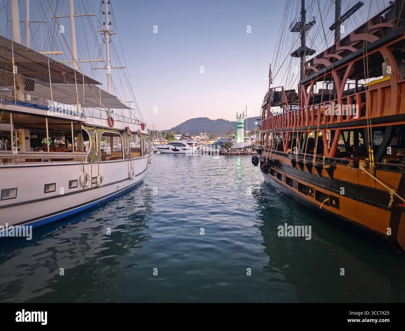 Kemer marina at dusk, filled with multiple docked boats. Lights of the ...