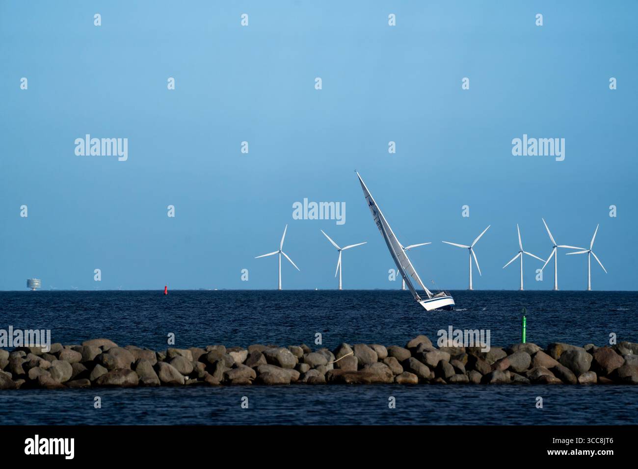 Sailboat and Offshore Wind Turbines beyond Rocky Breakwater Stock Photo ...