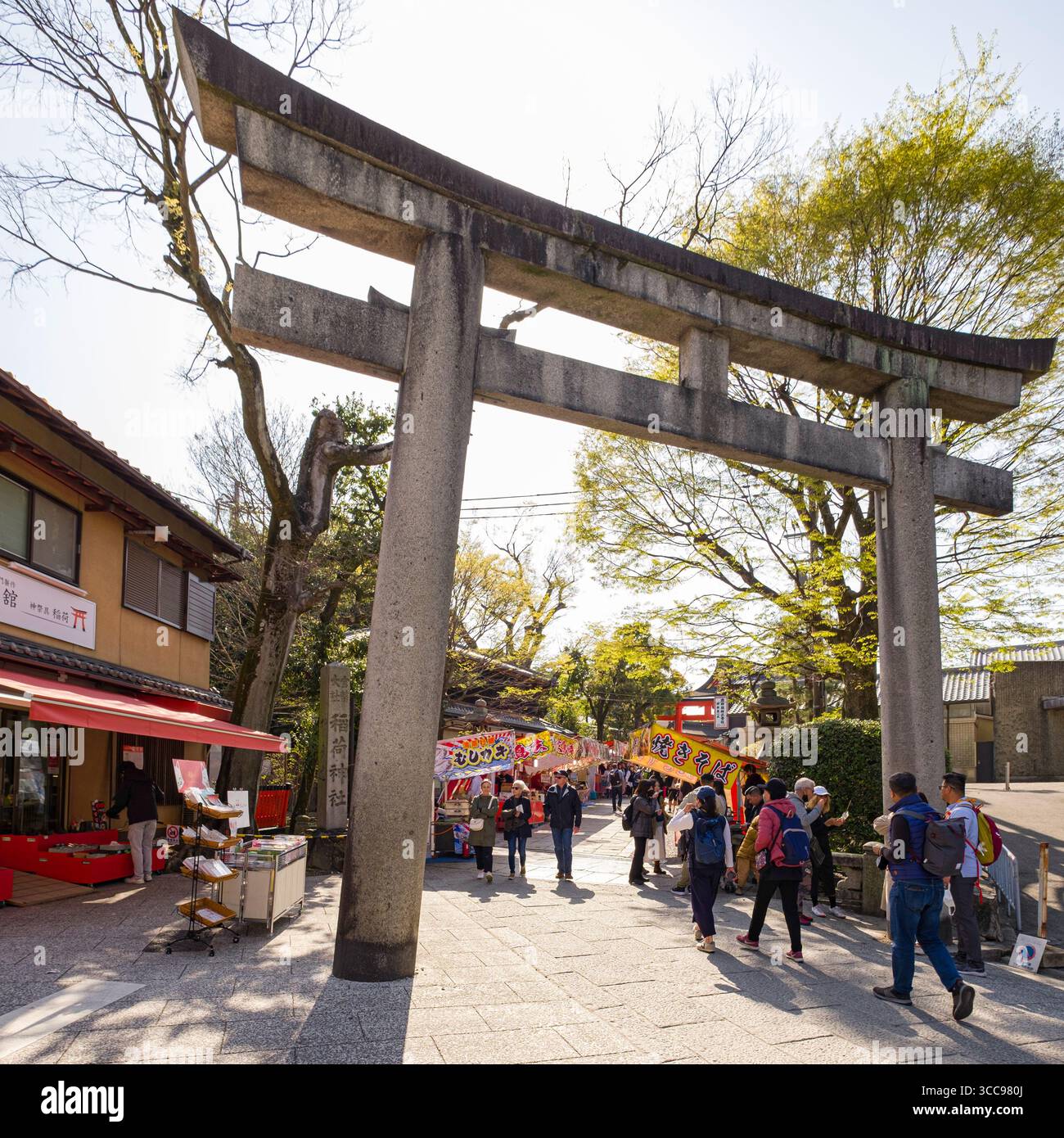 People walking under large stone back approach torii gate, Fukakusa ...
