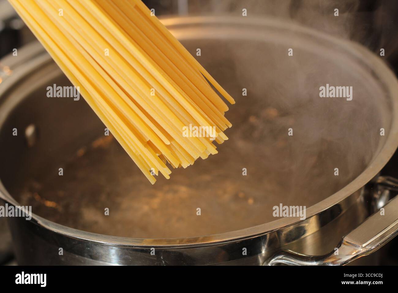 Closeup of Linguine Pasta Being Added to Boiling Water in Pot Stock ...