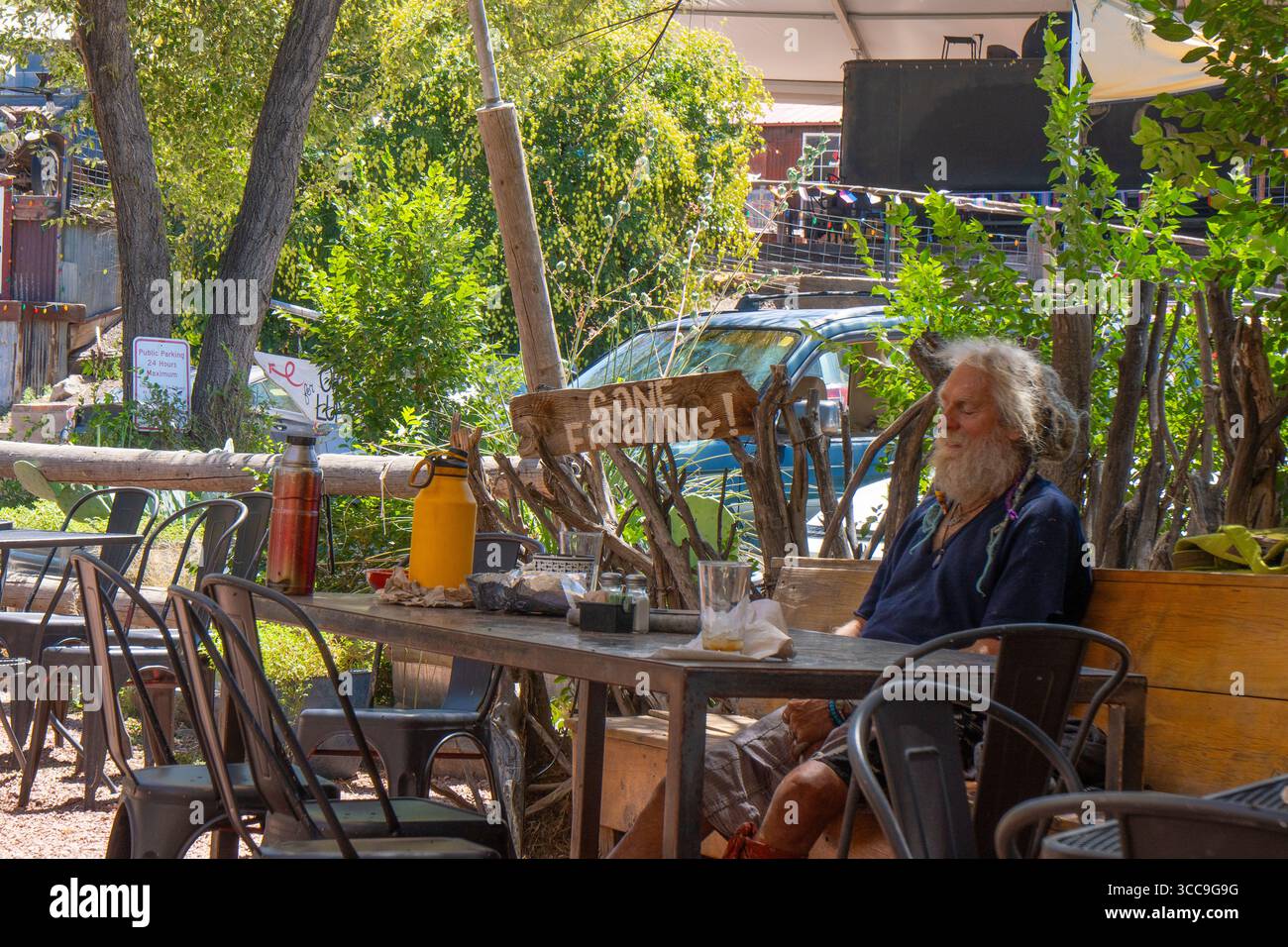 An older male naps after his lunch adjacent to a Gone Fishing sign ...