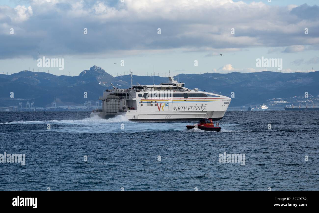 A Virtu Ferries ship sails on a calm sea with a small red pilot boat ...