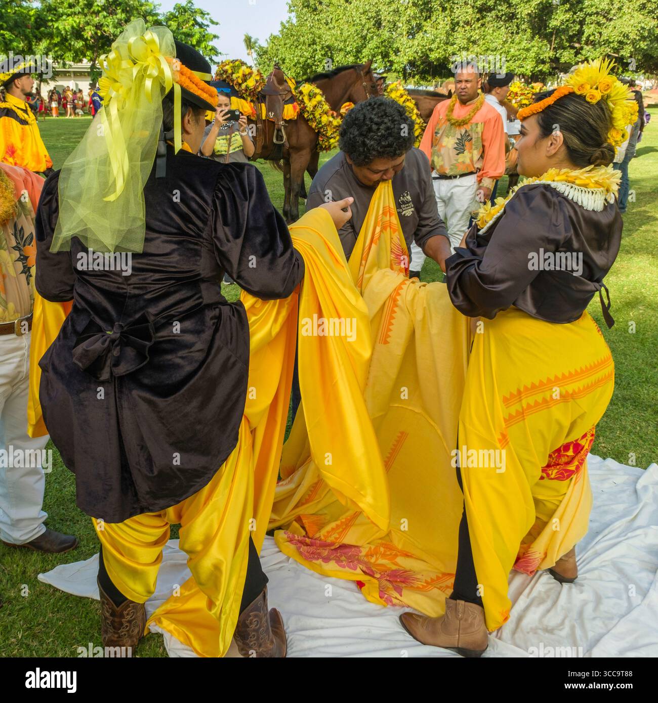 Man helping to dress a female Pa’u rider before the start of the Aloha ...