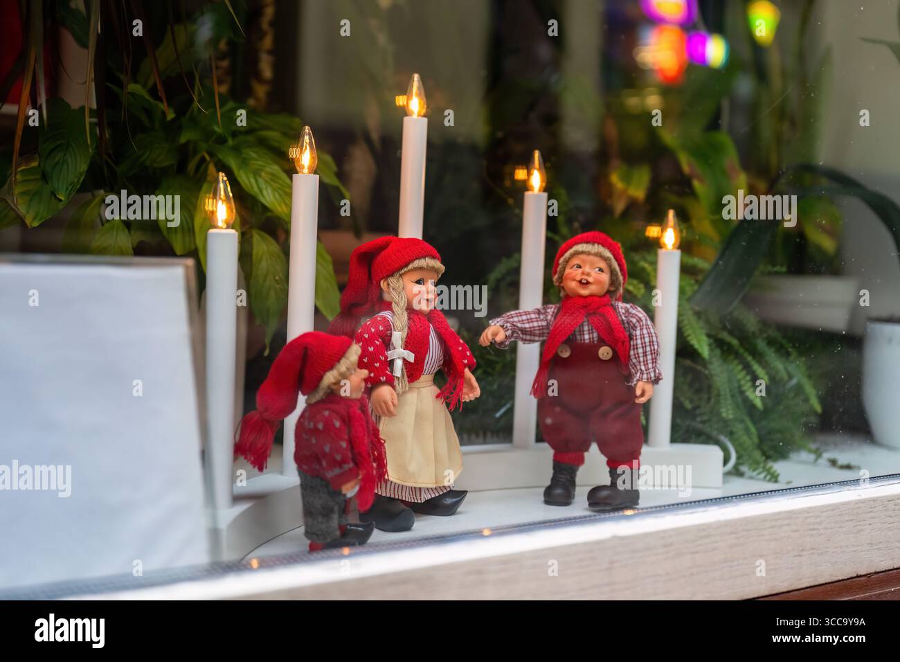 Christmas elf dolls in red clothes with candles in festive window ...