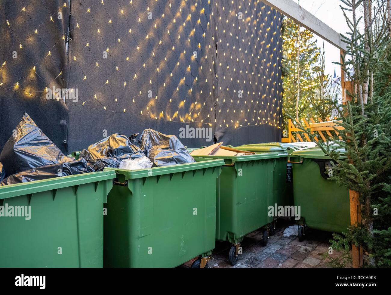 Green garbage bins with trash bags near Christmas tree and festive ...
