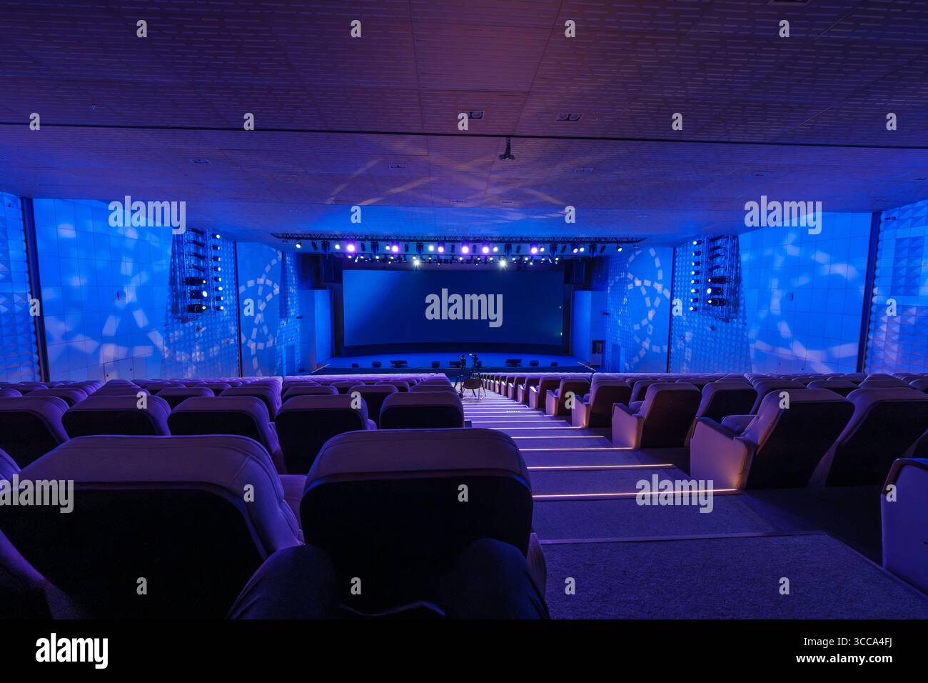 Modern theater interior with blue illumination, rows of seats, and ...