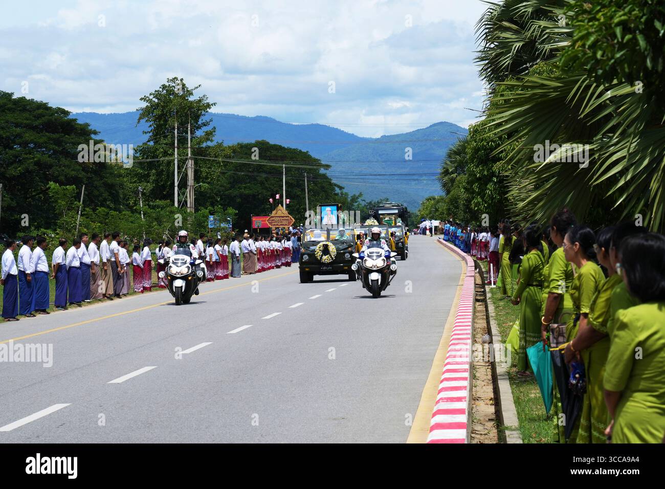 People stand beside a road while convey carrying coffin of former ...