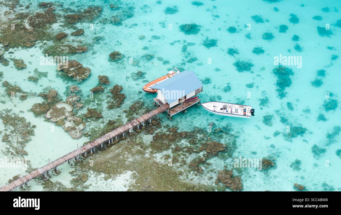Aerial view of a stilt house with a wooden walkway and boats floating ...