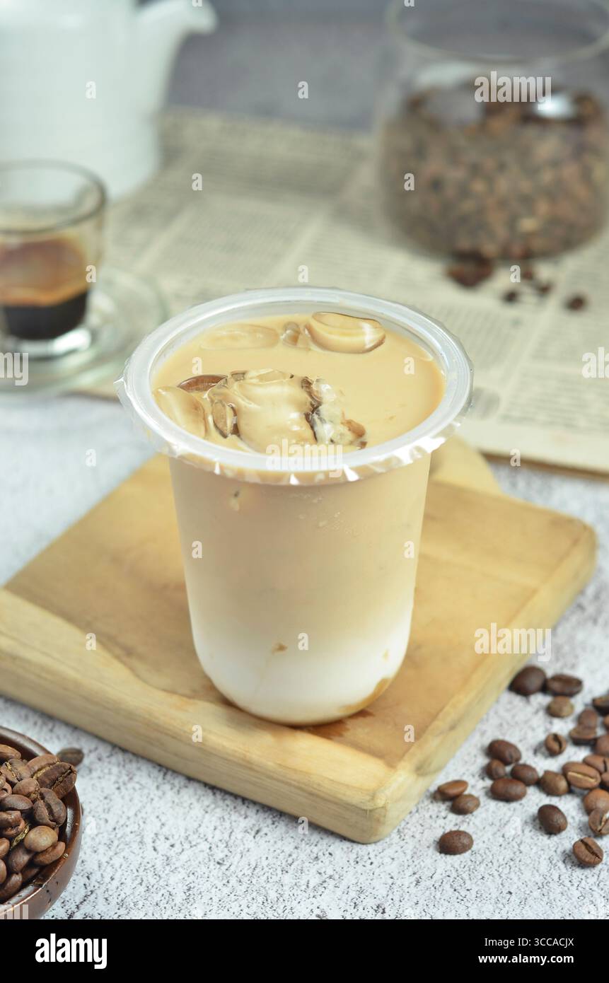 Ice coffee in a plastic cup with brown sugar and ice cubes and beans ...
