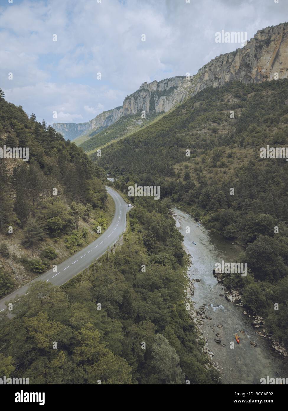 Aerial view of a winding road carving through lush greenery alongside ...
