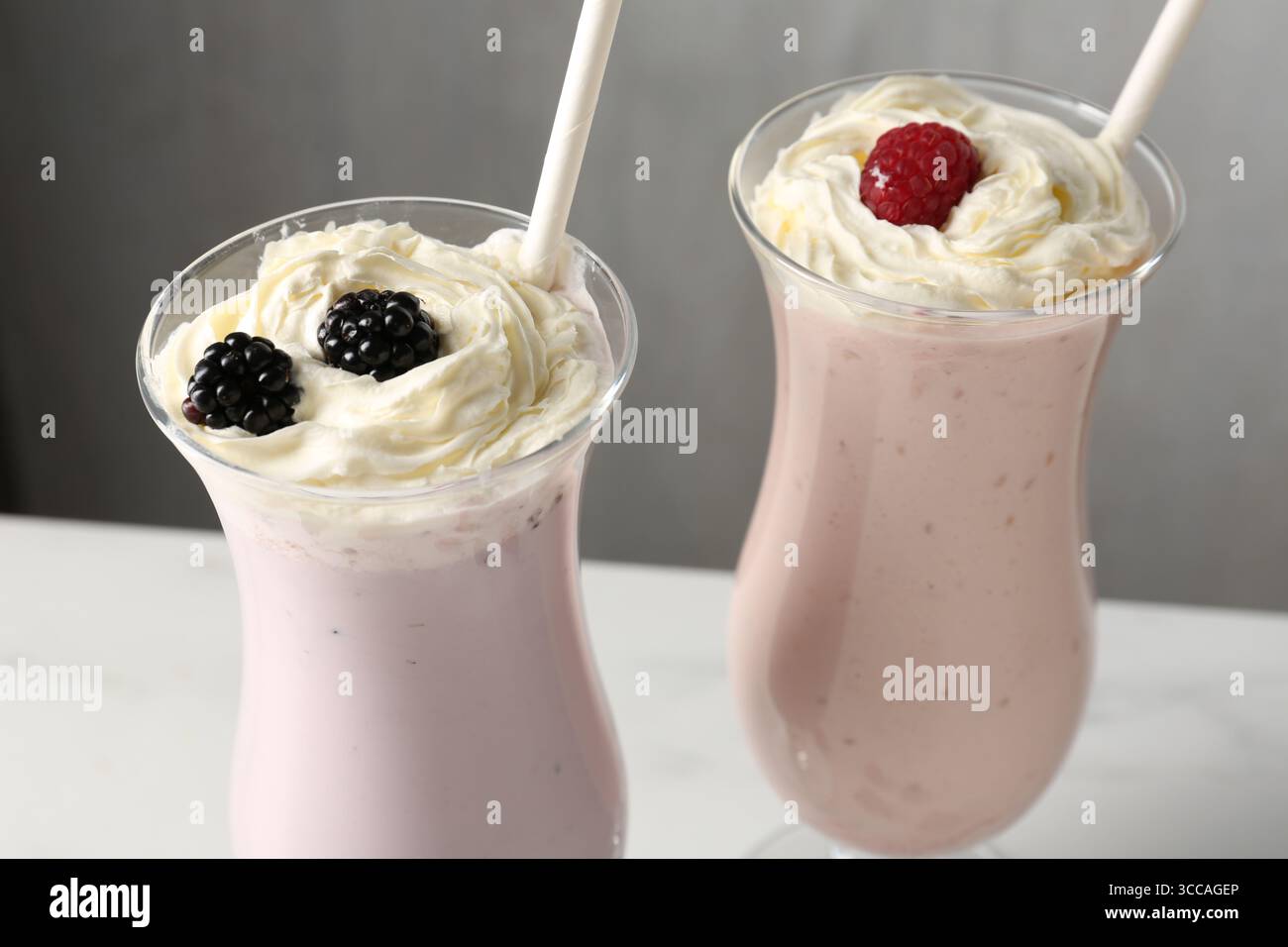Different tasty milkshakes with whipped cream in glasses and berries on ...