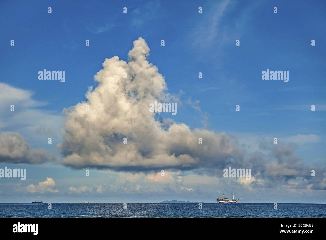 Large cumulus cloud and liveaboard submersible, Raja-Ampat, Kri Island ...