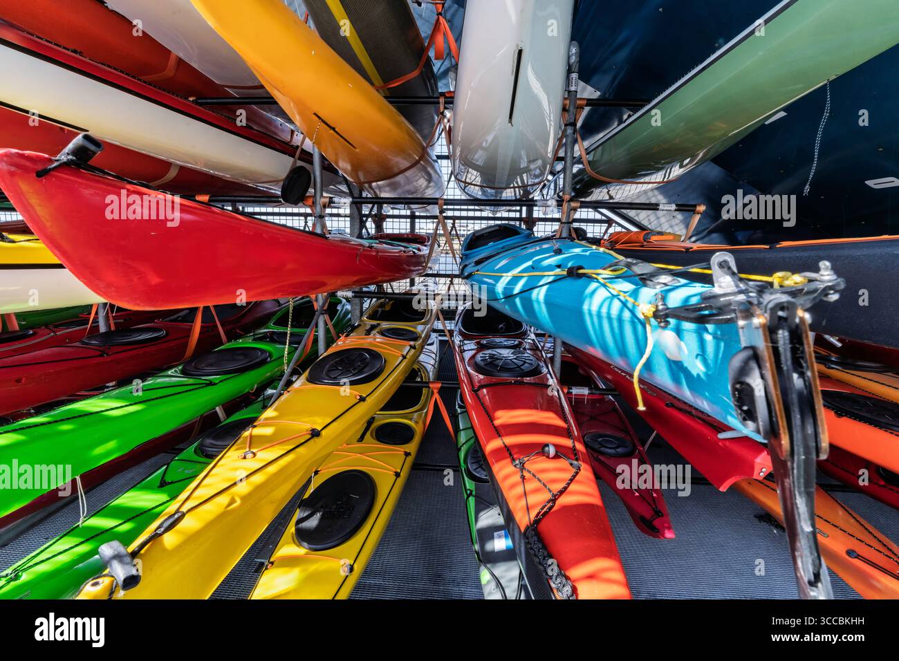 A vibrant collection of brightly colored kayaks stored in an organized ...