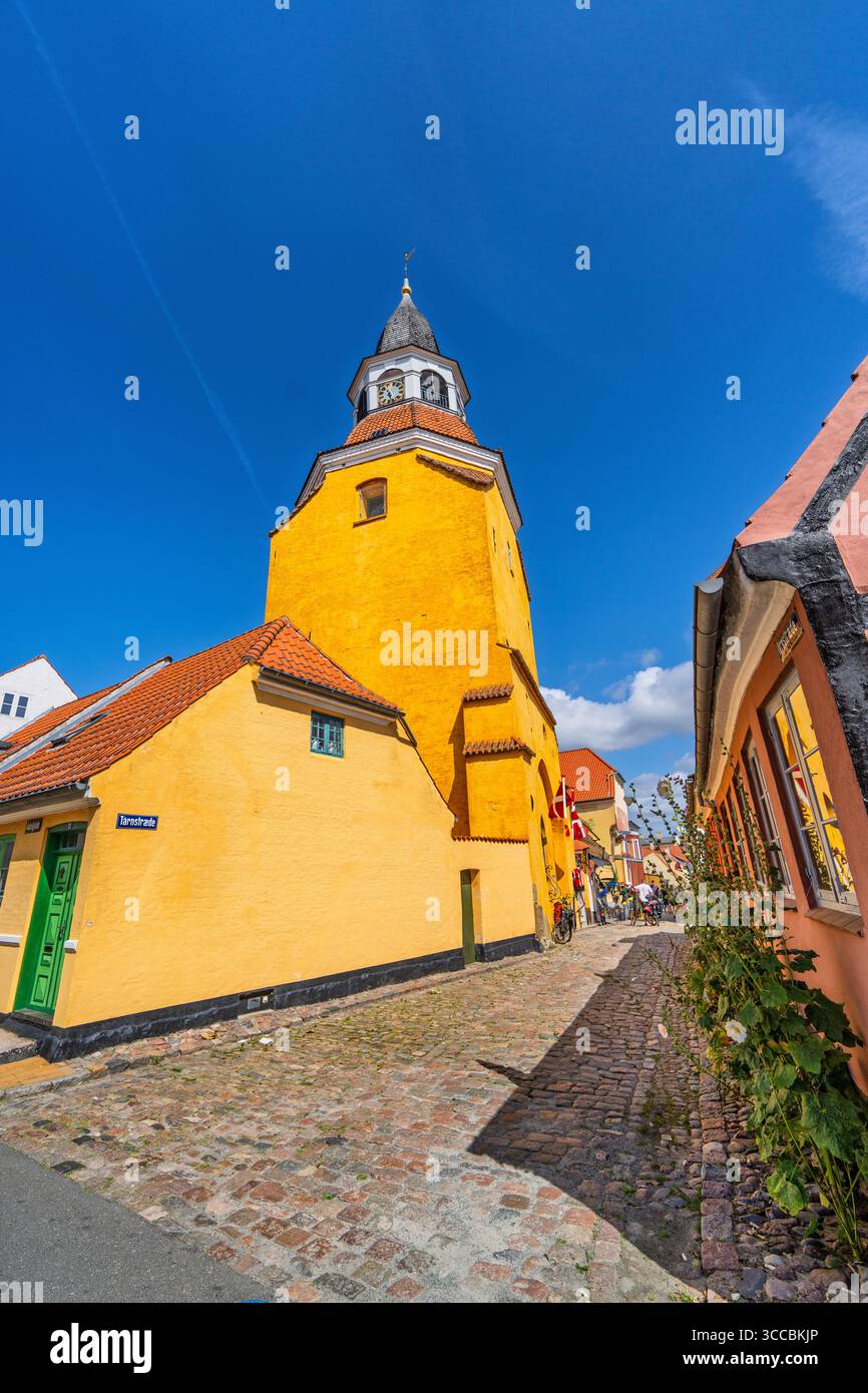 Bright yellow church tower in a charming village with cobblestone ...