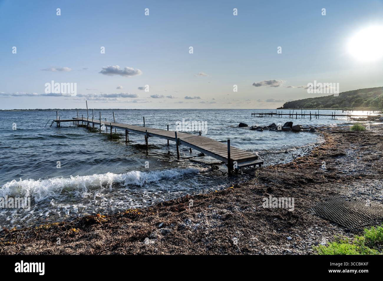 A serene coastal scene featuring a wooden dock extending into gentle ...