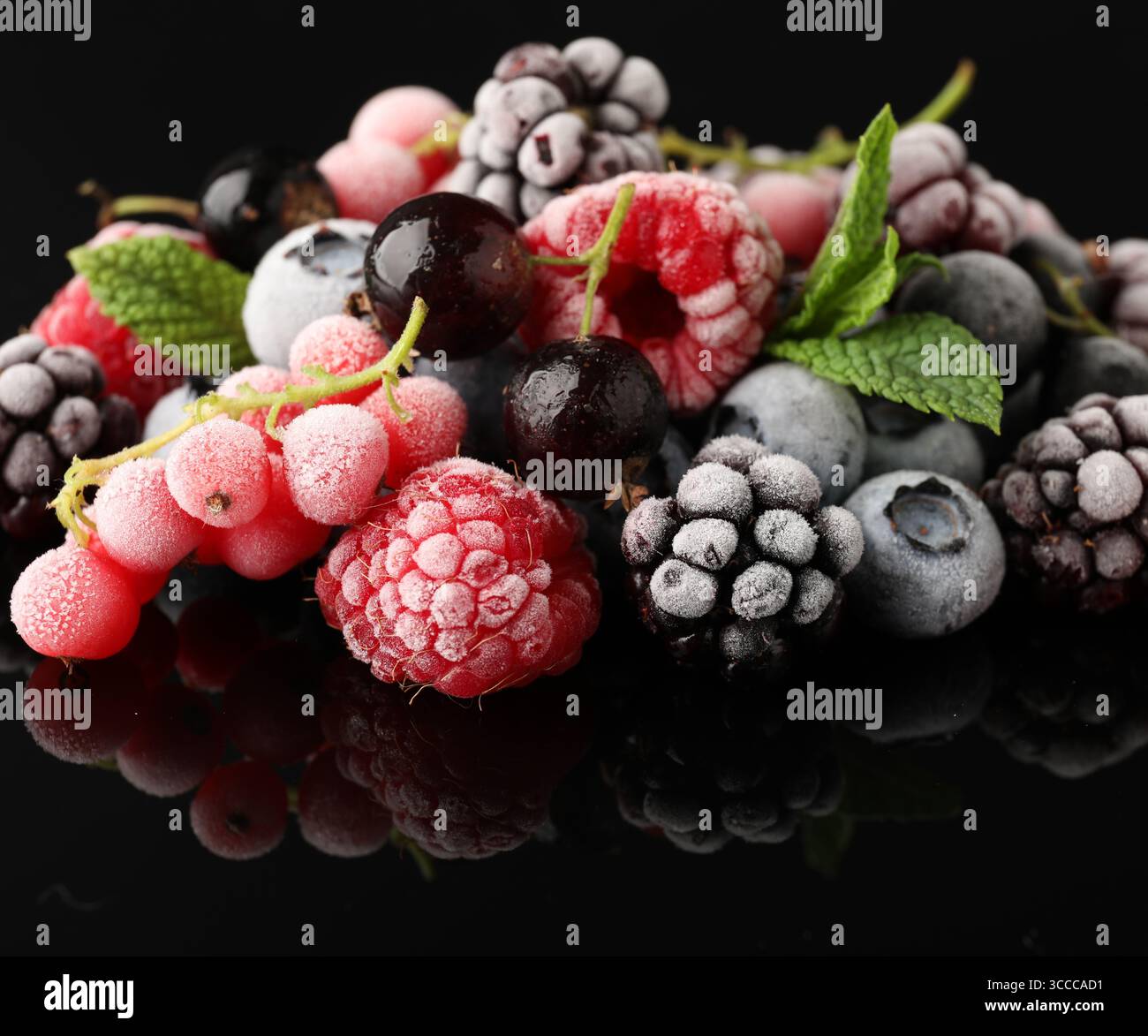 Many different frozen berries and mint on black table, closeup Stock ...