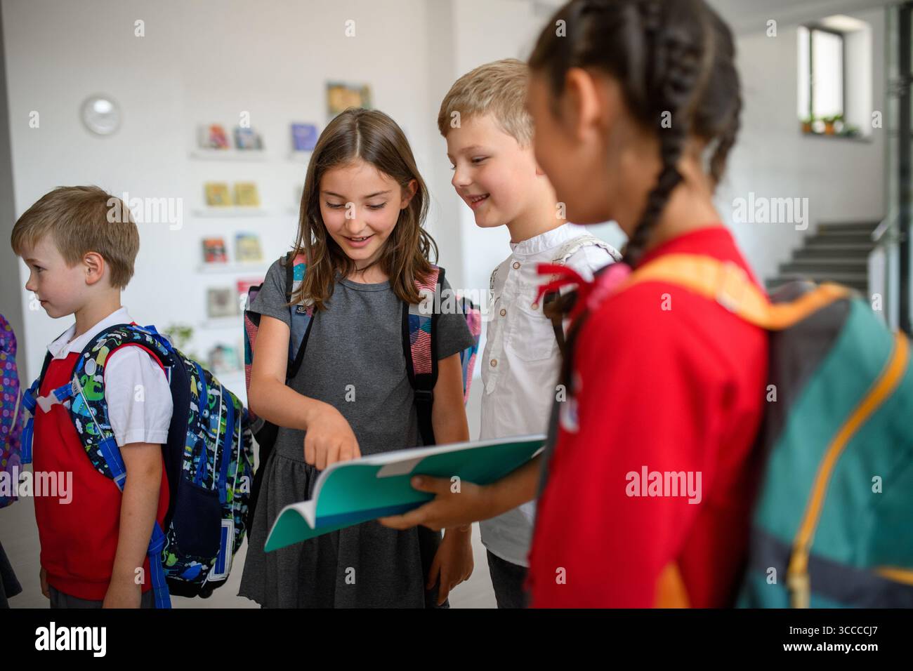Happy schoolkids talking in school hallway Stock Photo - Alamy