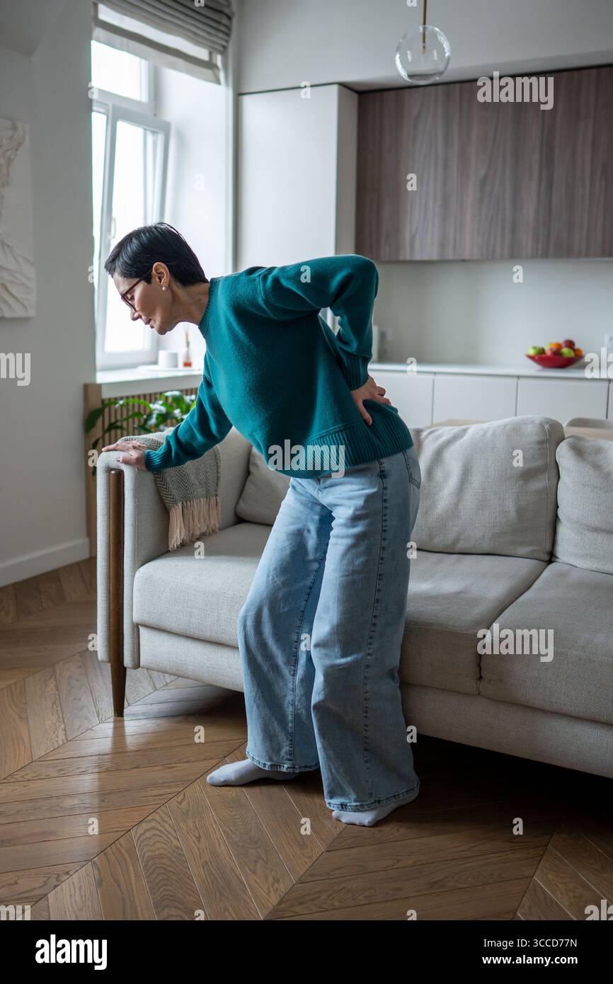 Senior woman gripping lower back in severe pain from spinal attack ...