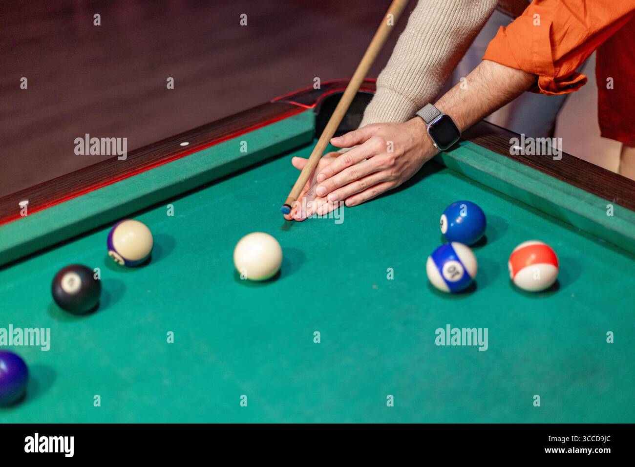 Two friends are playing billiards, aiming the white ball with the cue ...