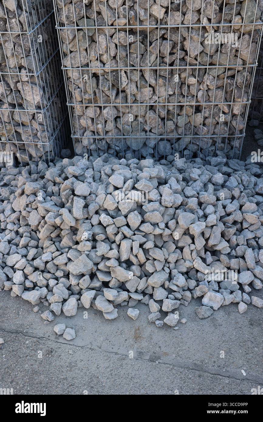 A pile of rocks is sitting on the ground next to a metal fence Stock ...