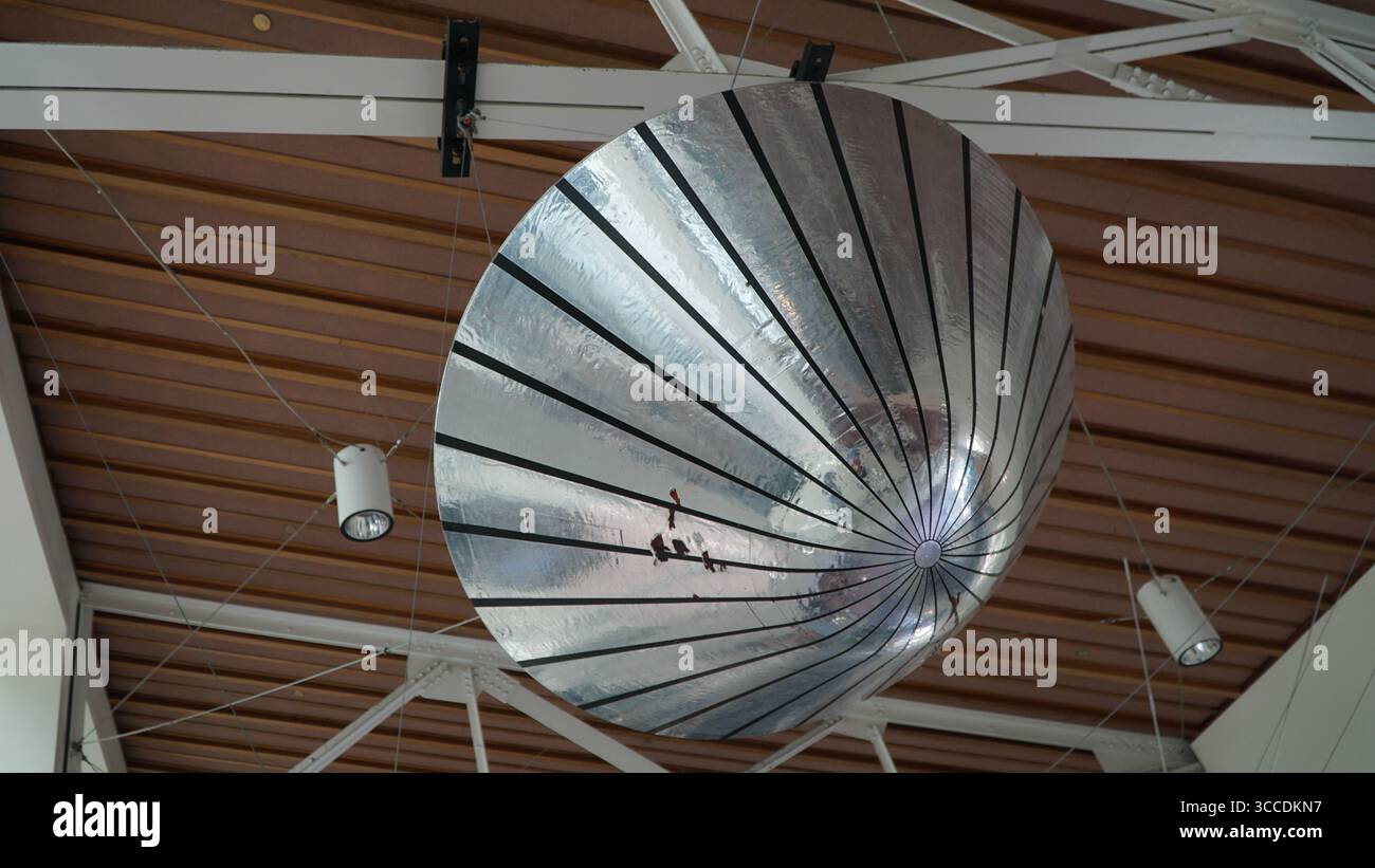 Close-up view of a large reflective parabolic dish suspended from the ...