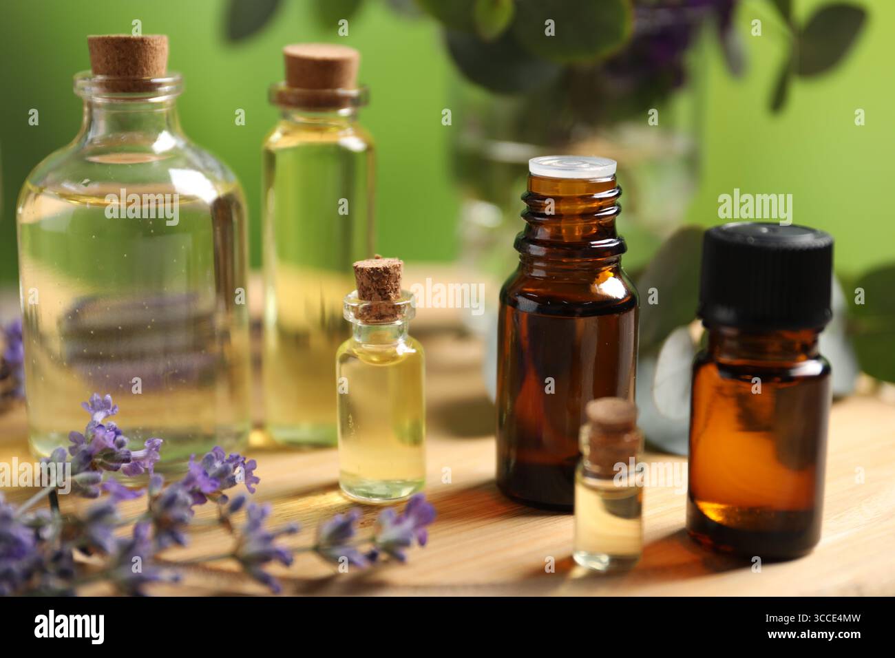 Bottles of essential oils and different plants on table outdoors ...