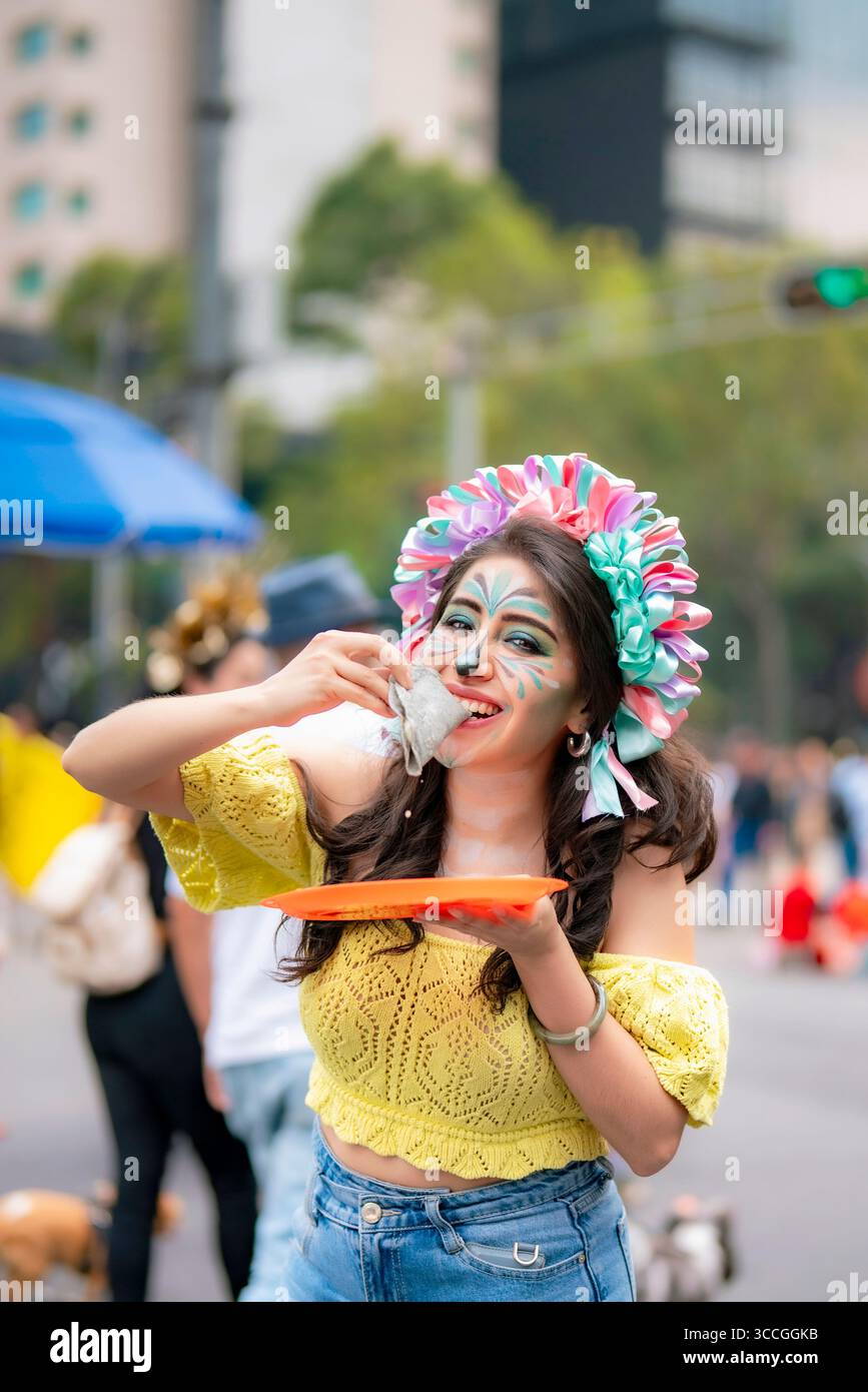 Smiling young happy Latina in catrina makeup eats street food ...