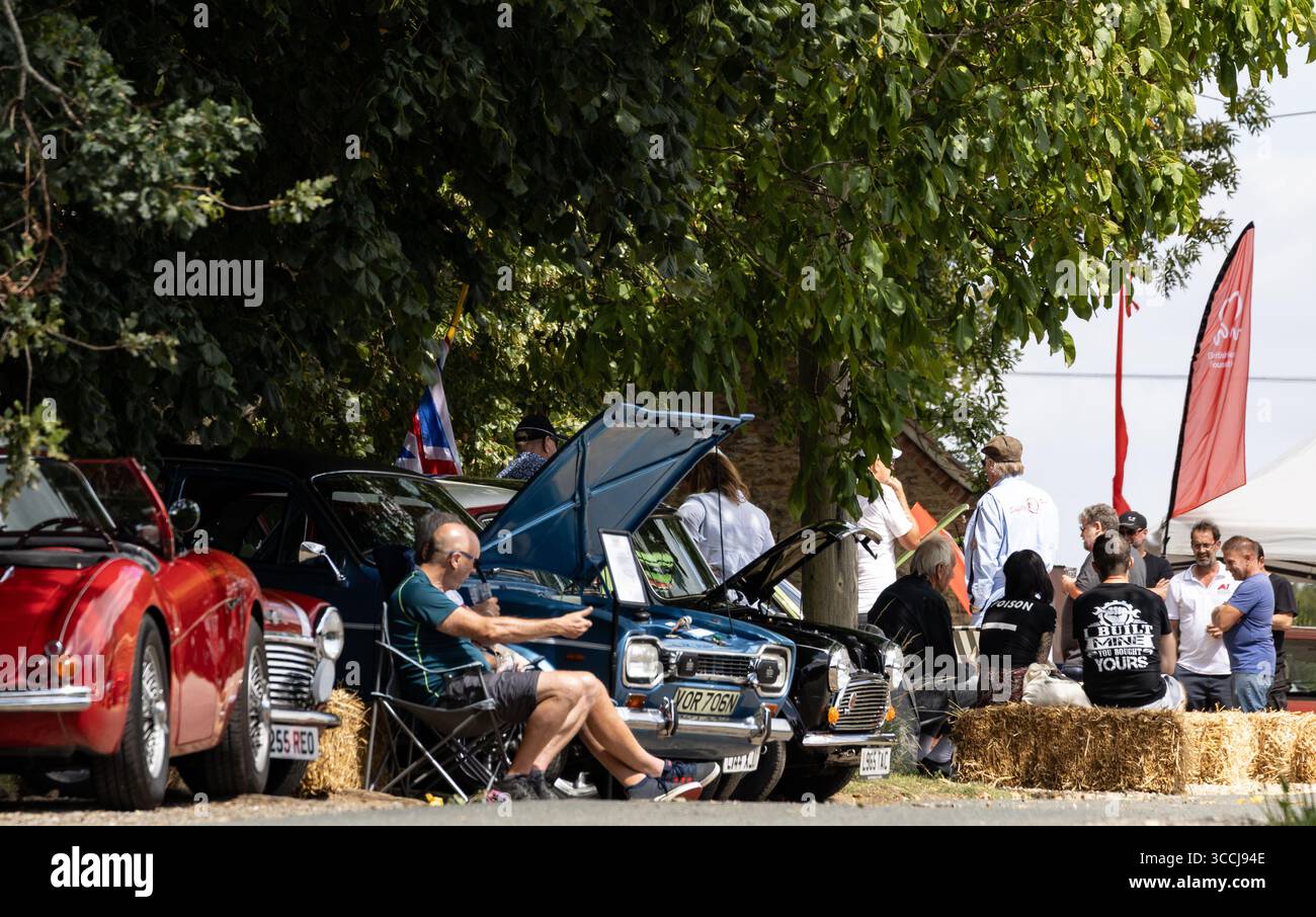 Classic car enthusiasts gather at an outdoor vintage auto show with ...