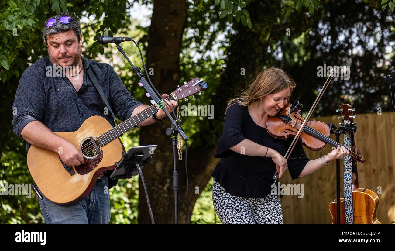 A duo of musicians performs outdoors with a guitarist and a violinist ...