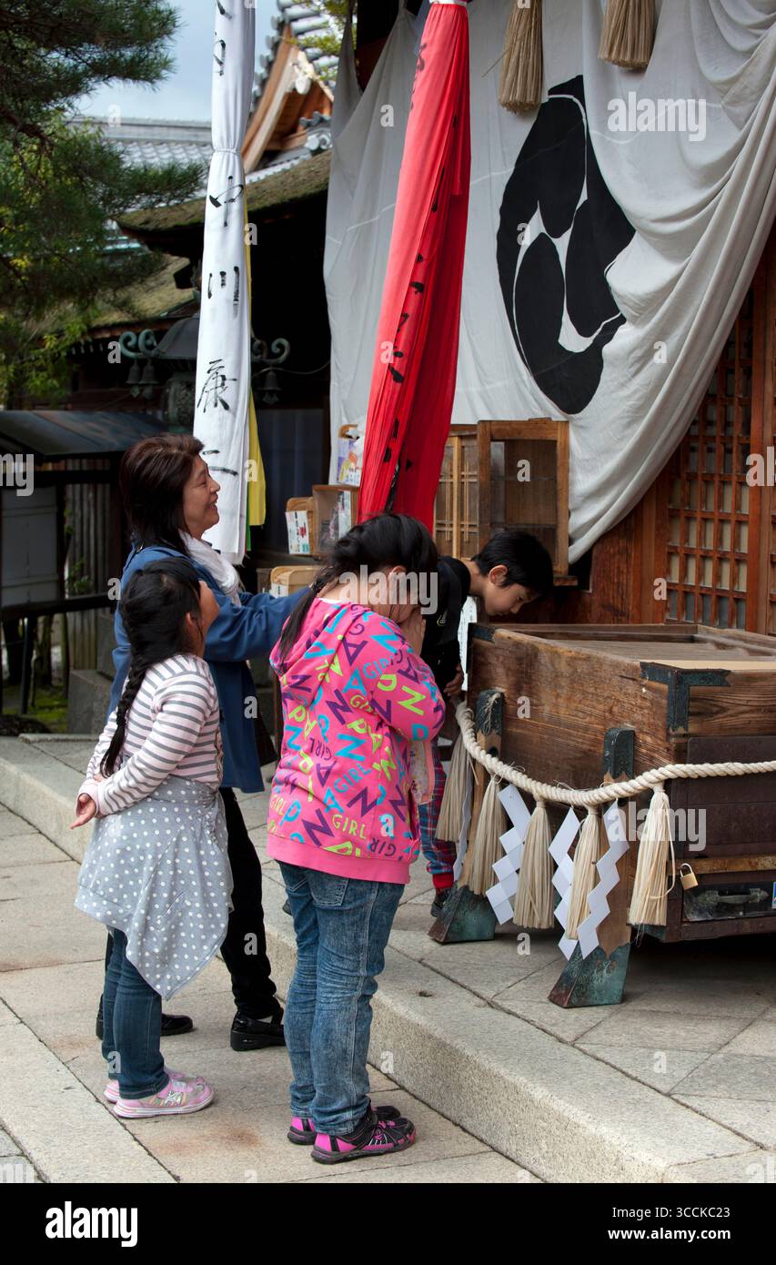 Japanese family with children taking a moment to pray to the deity at ...