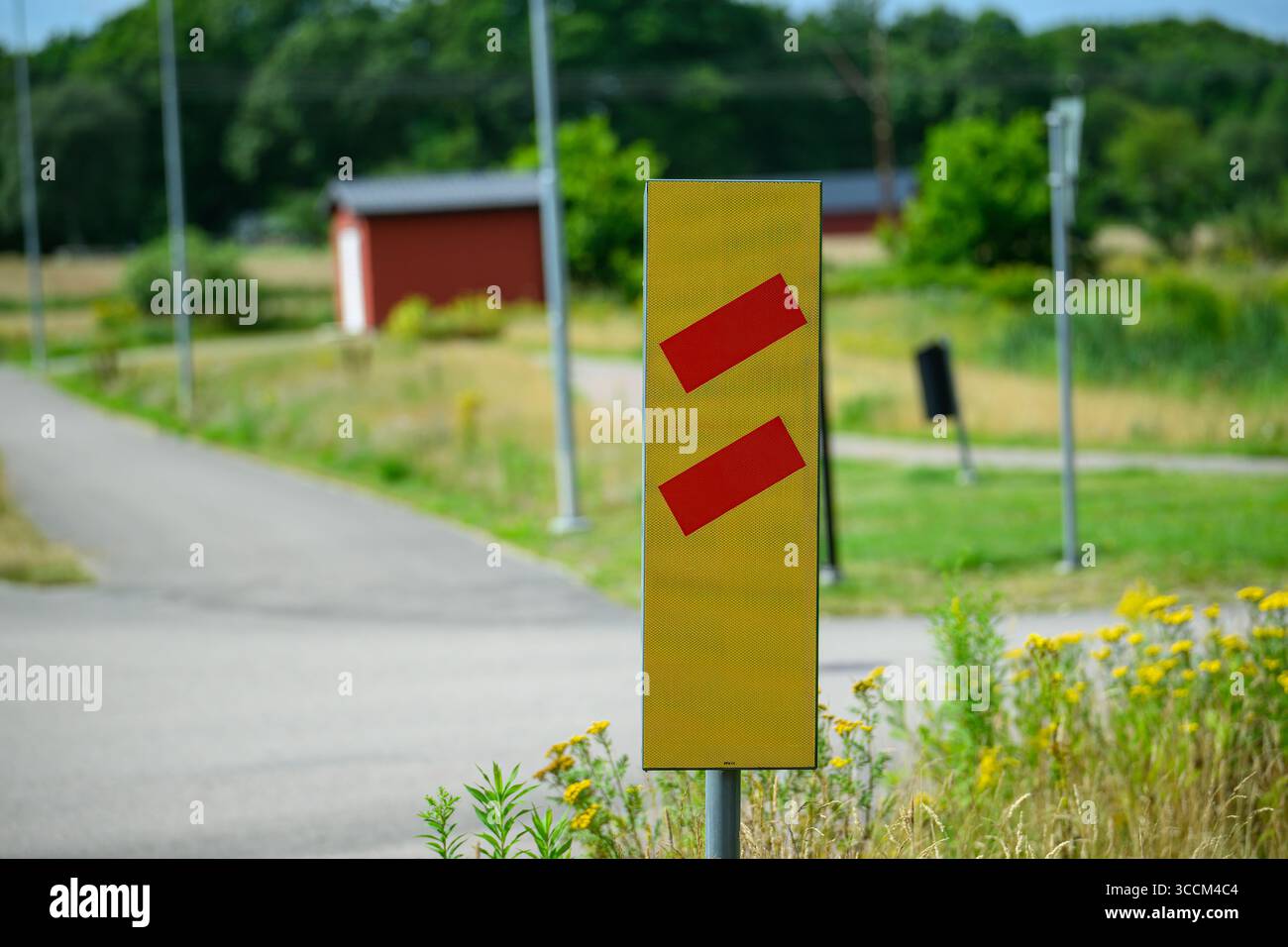 A traffic warning sign with two red lines stands by railroad crossing ...