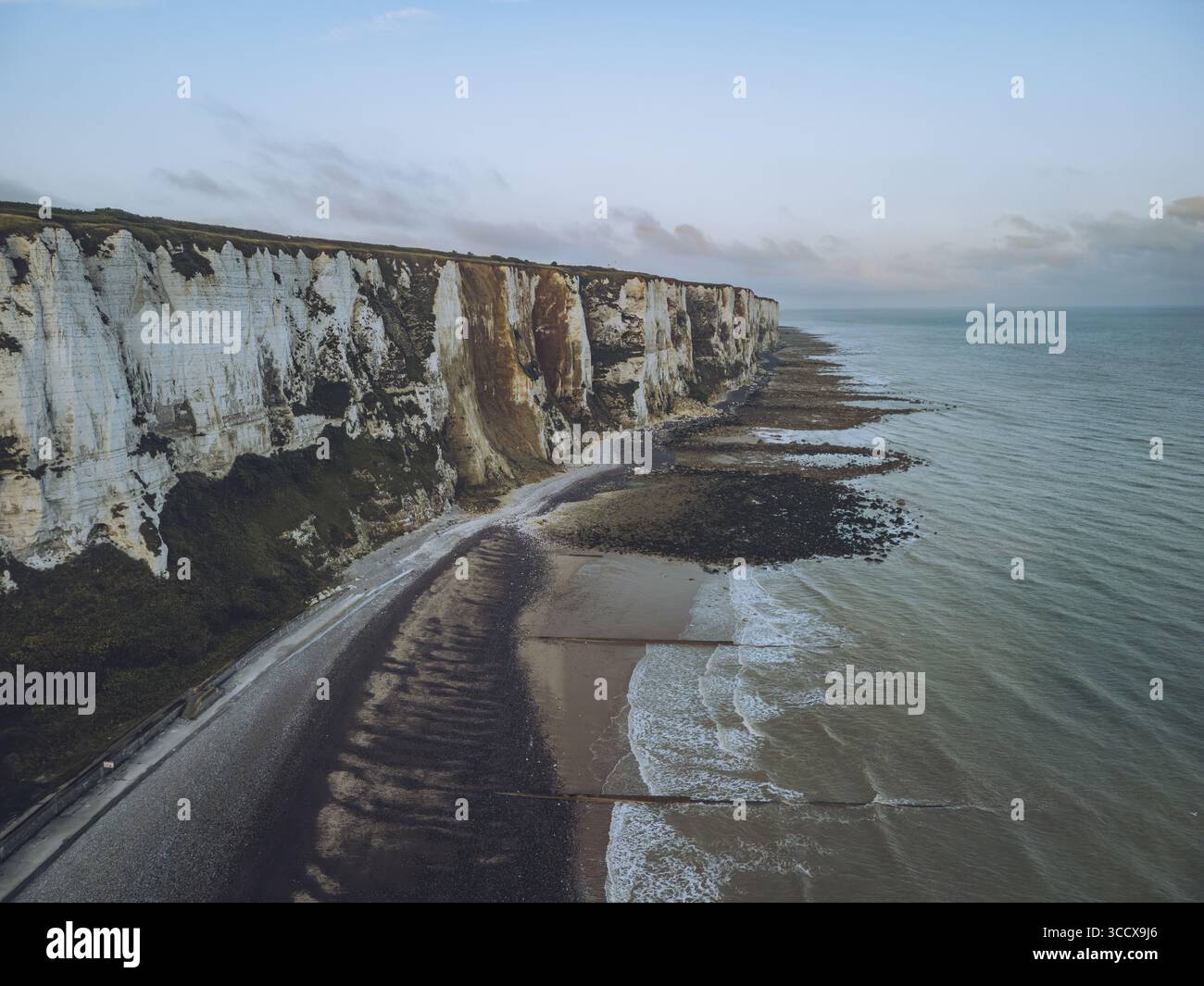 Aerial view of stark white cliffs meet the frothy, turbulent sea ...