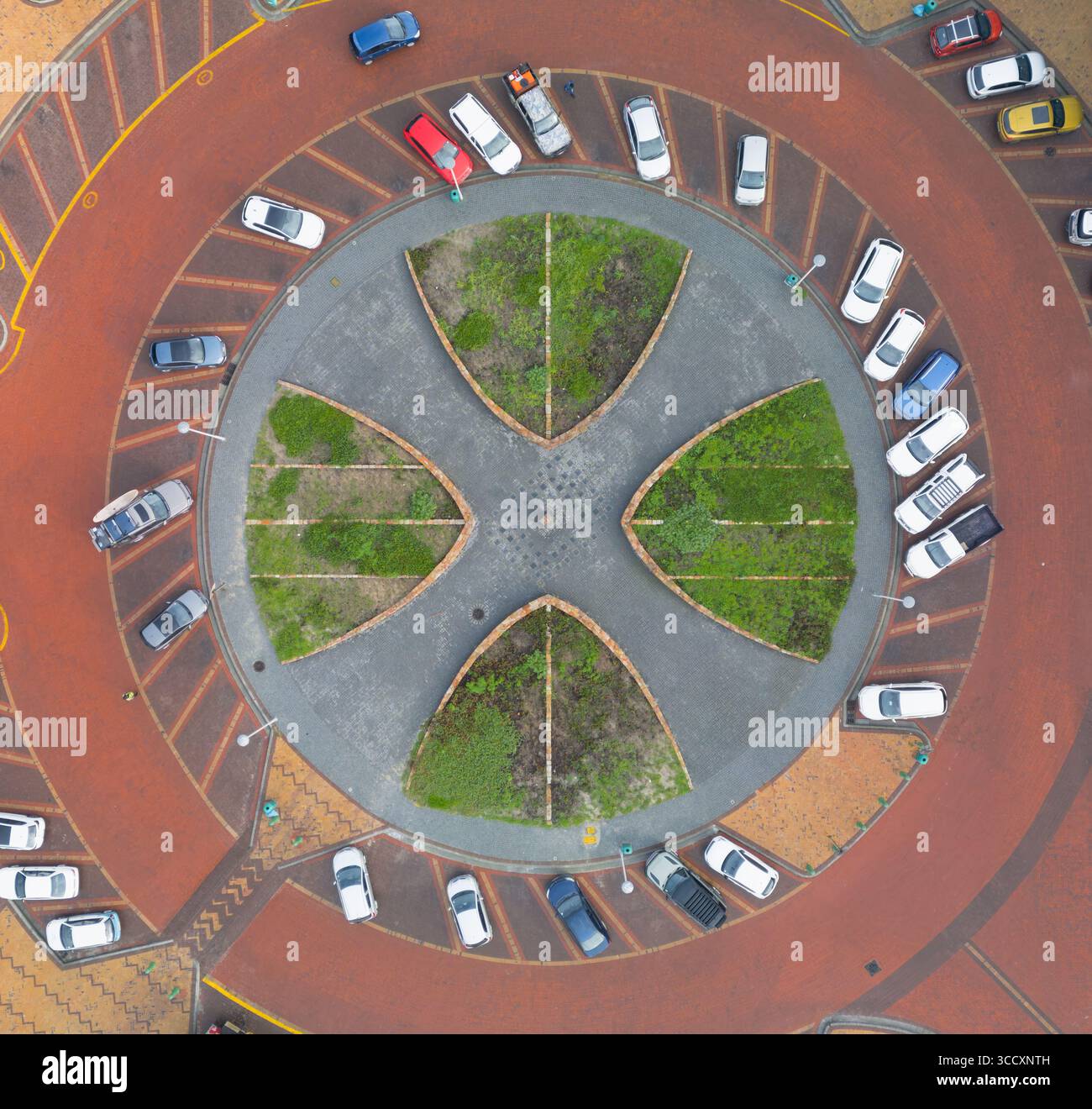 Aerial view of cars parked around a roundabout with green spaces in a ...
