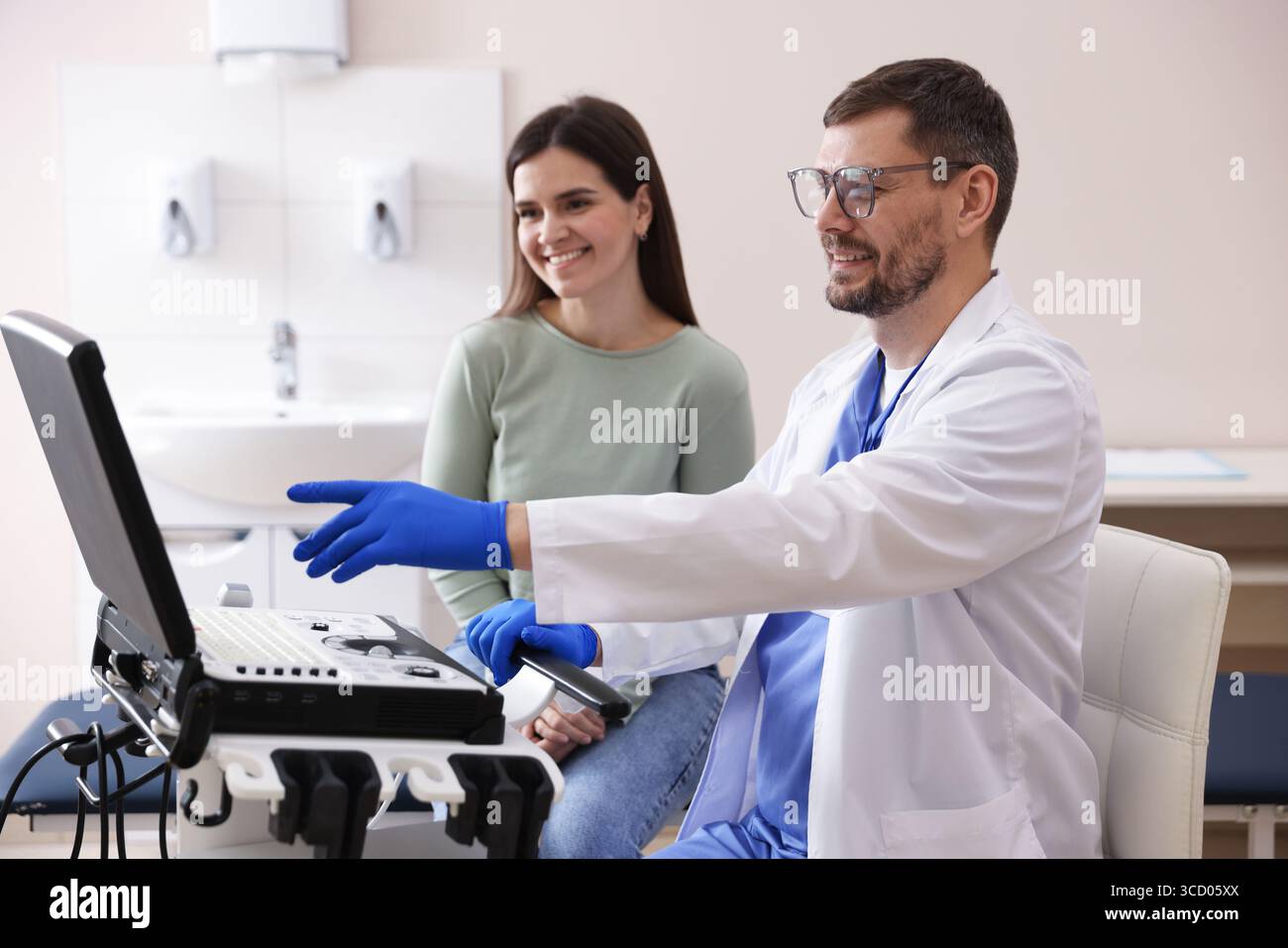 Sonographer showing woman her ultrasound imaging on screen in clinic ...