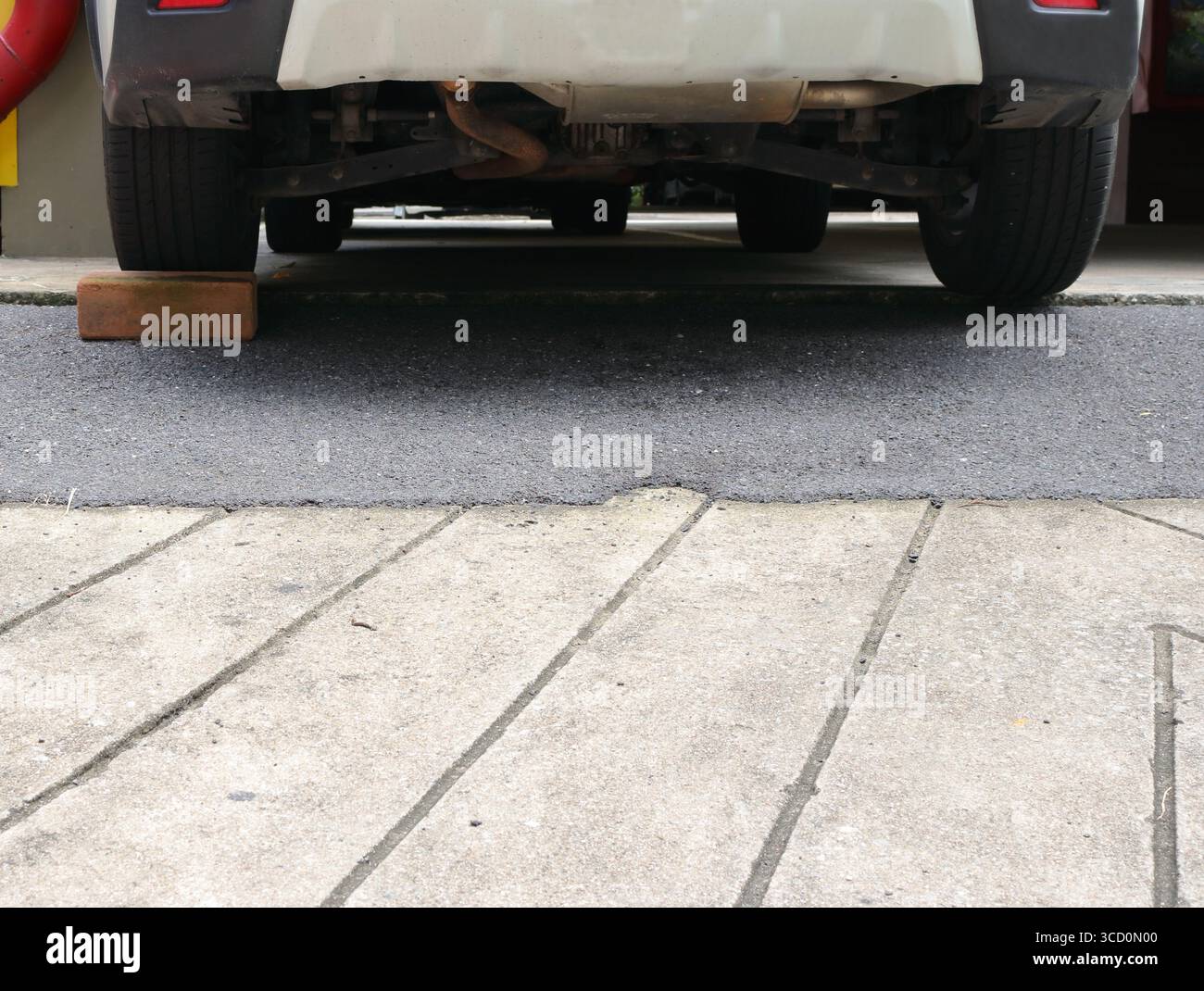A brick is placed against rear wheel of a parked car to prevent it from ...