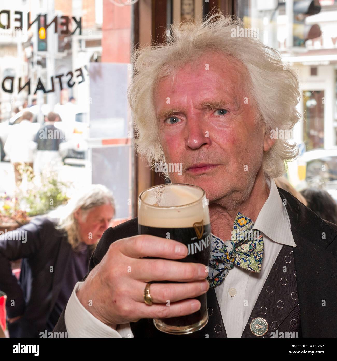 Sliver haired man holding up a glass pint of Guinness beer during ...