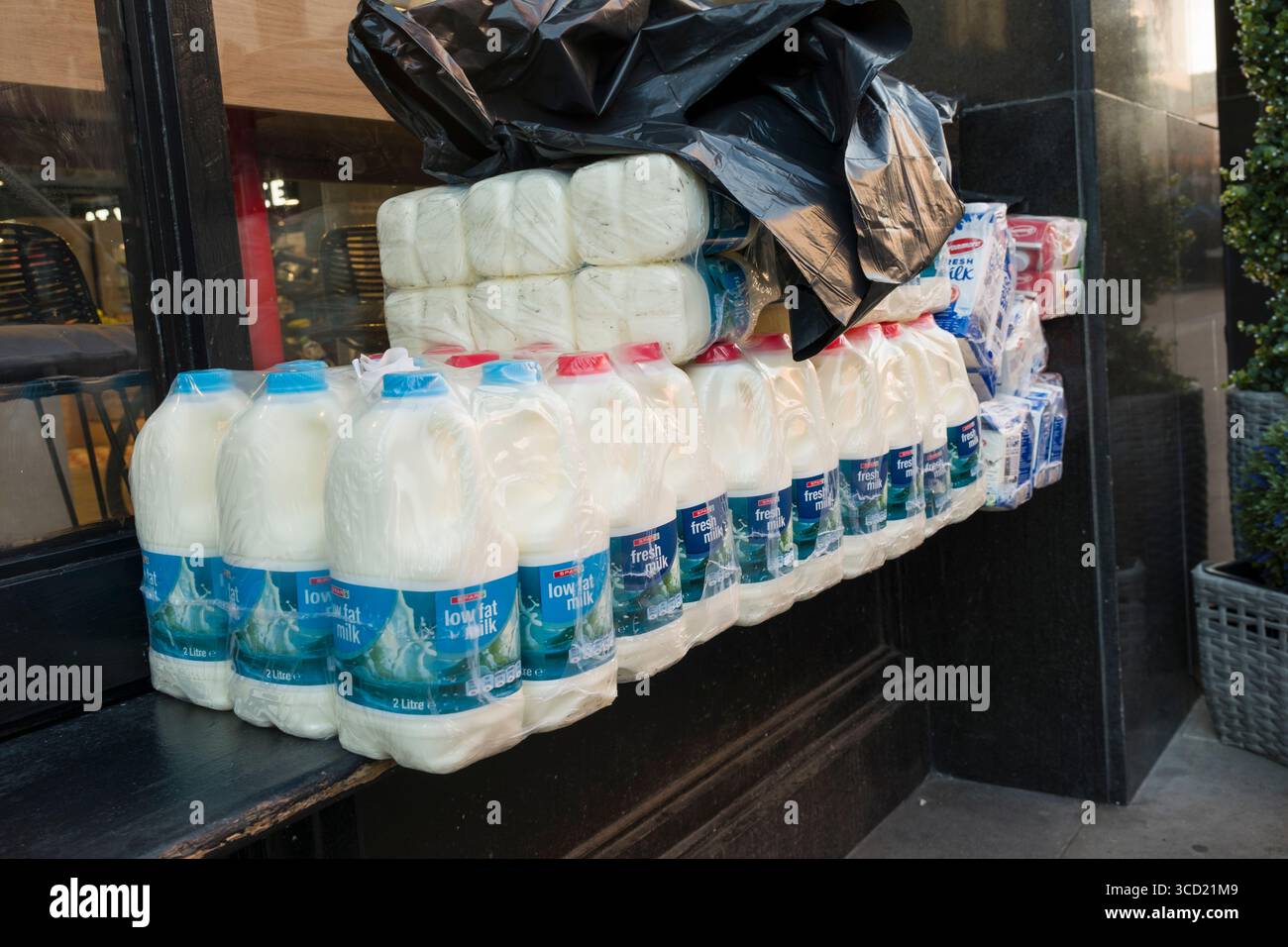 Plastic wrapped 2-liter containers of fresh milk on bench outside of ...